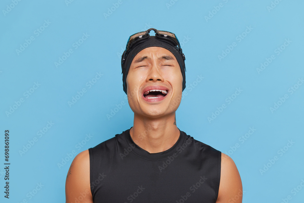 Young sportsman in black swimsuit poses on background crying about fail ...