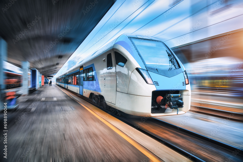 High speed train in motion on the railway station at sunset. Blue ...