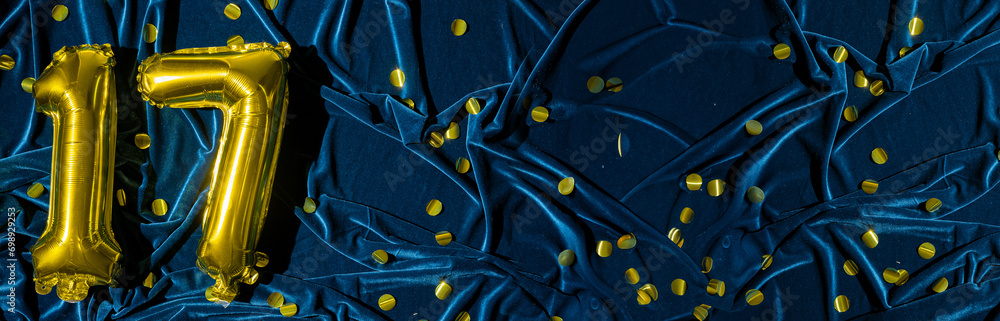 number seventeen, gold foil balloon number on a blue velvet background ...