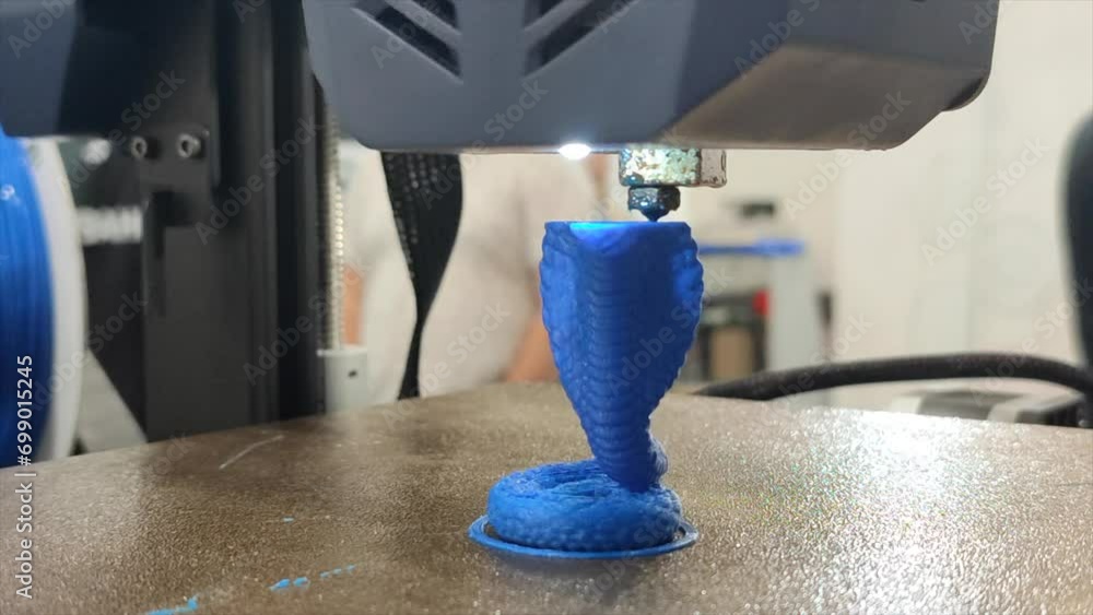 3D printer working close-up. 3D printer prints a model from molten blue ...