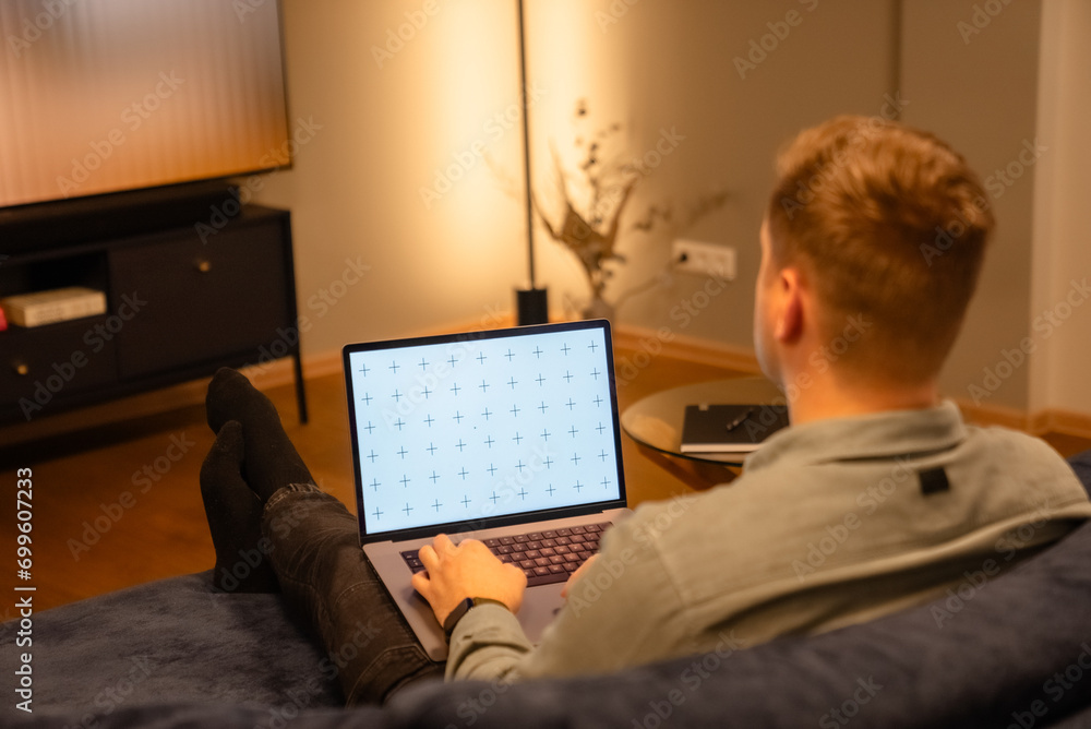 Man working, laptop in a lap, glass table, browsing computer with blank ...