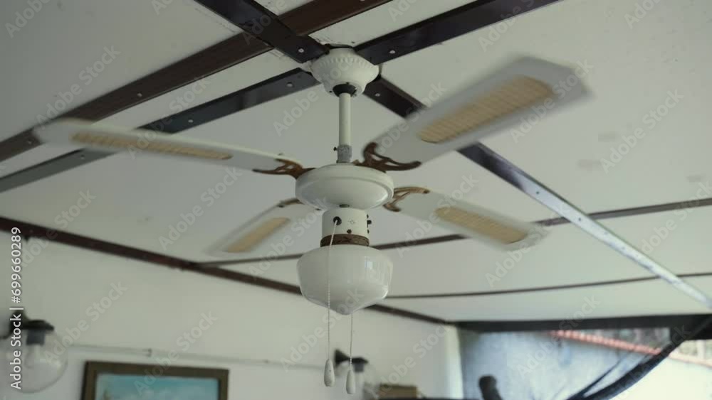 Old white ceiling fan with electric lamp spinning and cooling air ...