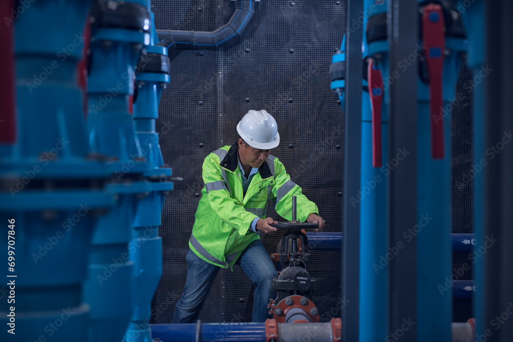 Service engineer in PPE open- close Valve in the pump room. Asia male ...