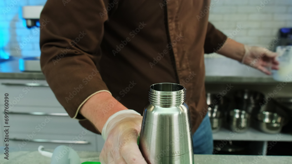 Chef screws lid of whipping siphon on table closeup. Man uses molecular ...