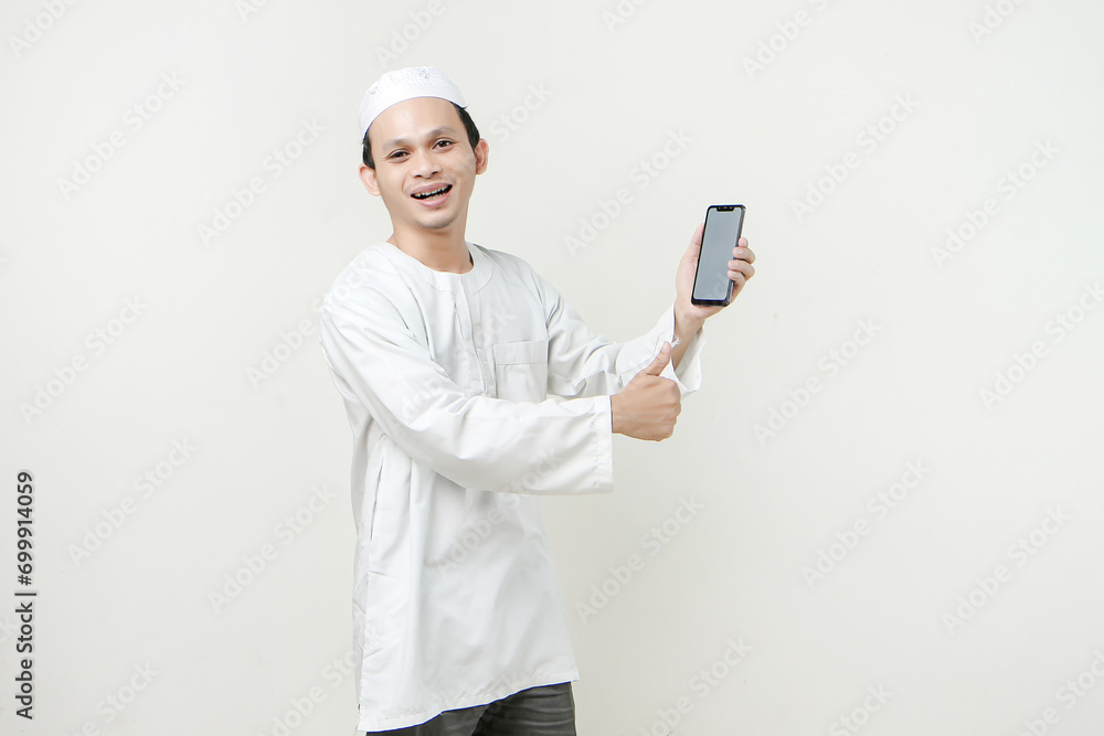 Asian Muslim man holding smartphone and showing thumb up gesture on ...