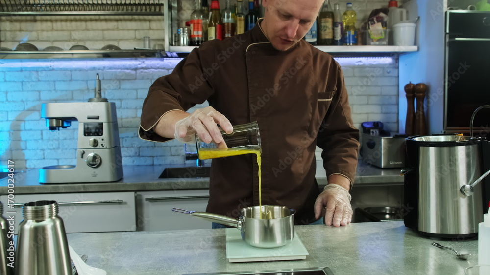 Skilled chef positions saucepan on scale accurately measuring necessary ...