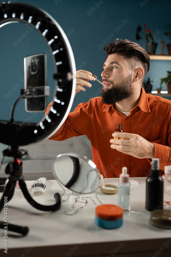 Male beauty blogger with beard oil or serum recording video in the ...