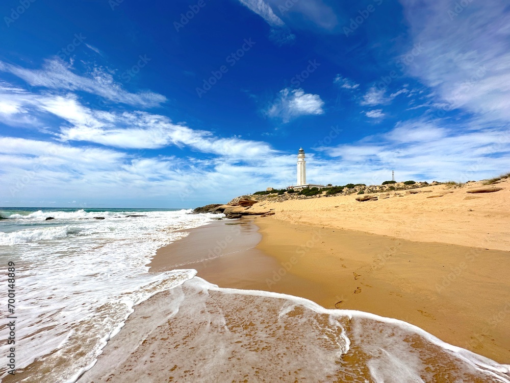 Faro de Trafalgar, vista desde la playa hasta el faro en un promontorio arenoso con dunas entre ...