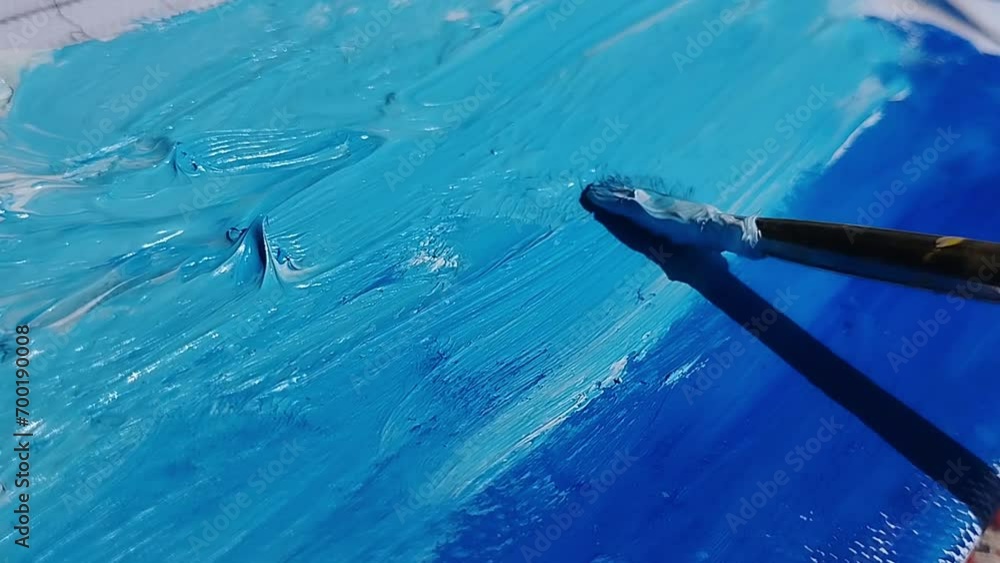Painting a blue background with oil paints on canvas. Mixing the colors ...