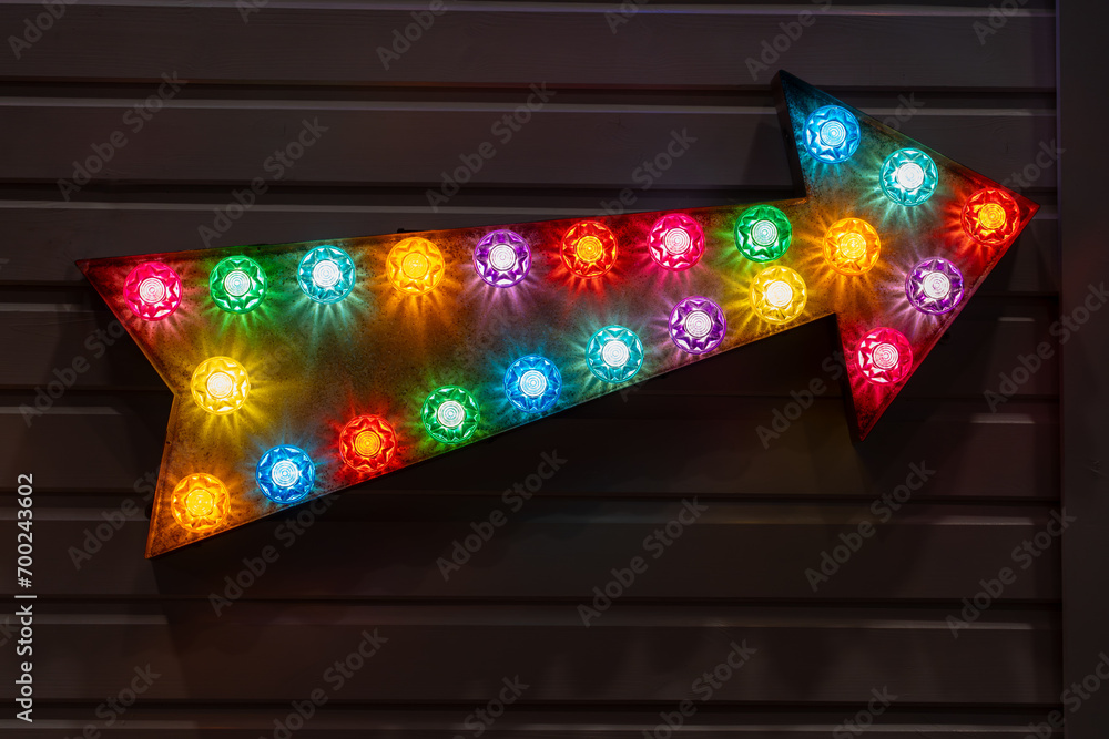 Poster Illuminated Arrow Sign with colored Bulbs Mounted to a Brown ...