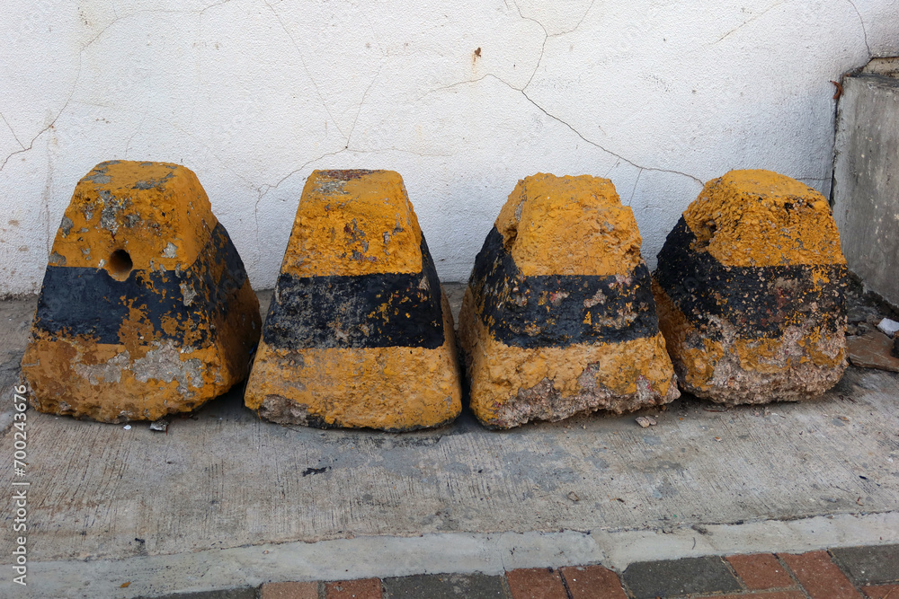 four old aged triangular pyramid shape yellow and black road rock ...