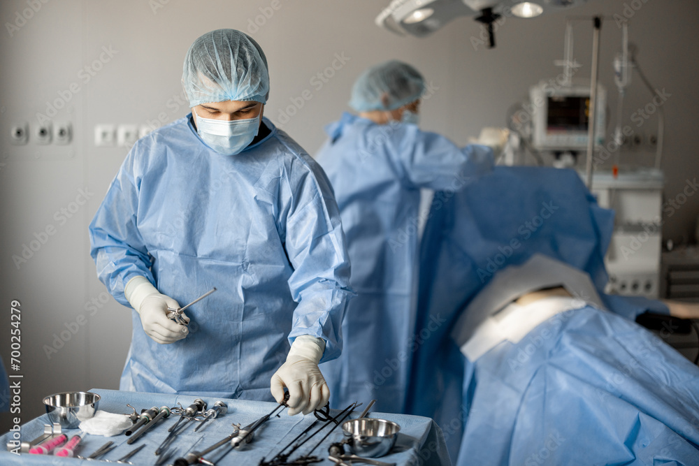 Surgeons in uniform prepare sterile medical instruments for surgery ...