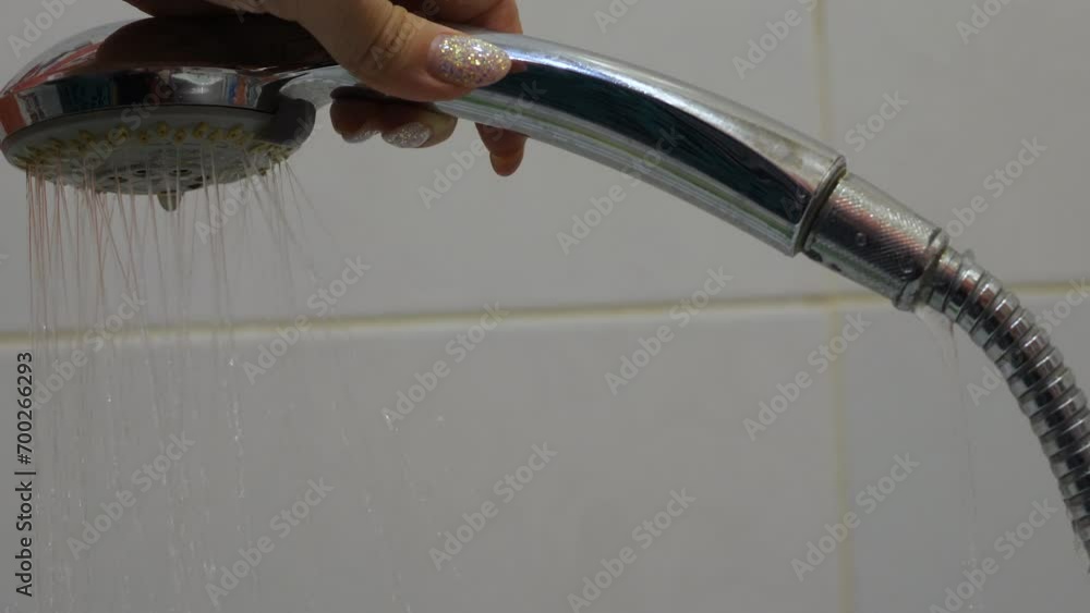 female hand holding a damaged broken shower with a flowing hose. faulty ...