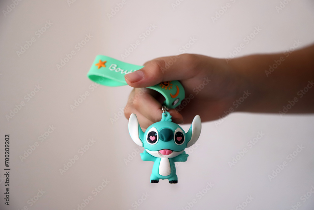 Children holding a Stitch character keychain in their hand. Animated ...