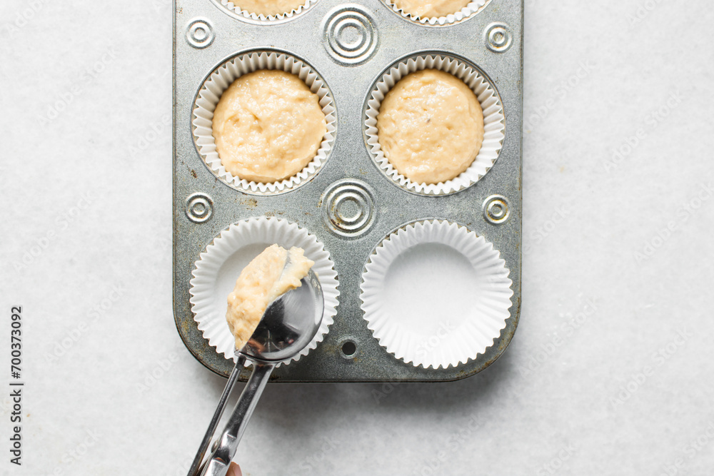 scooping vanilla almond muffins batter in a cupcake pan, top view of ...