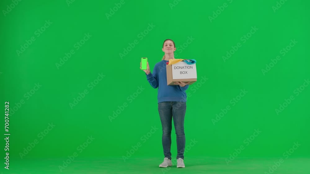 A woman volunteer holds a box full of clothes labeled Donation box. The ...