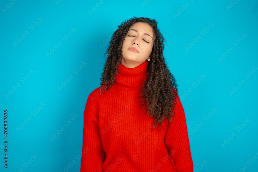 Beautiful teen girl wearing knitted red sweater over blue background ...