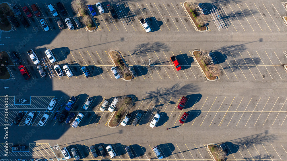 Top-down view of a parking lot with neatly aligned cars casting long ...