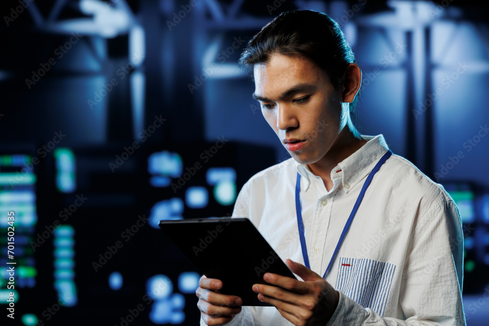 Tech support worker between server room equipment providing processing resources for businesses ...