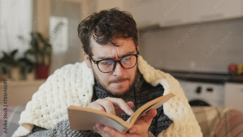 Vidéo Stock Chilled retreat Man wrapped in a duvet, reading with ...