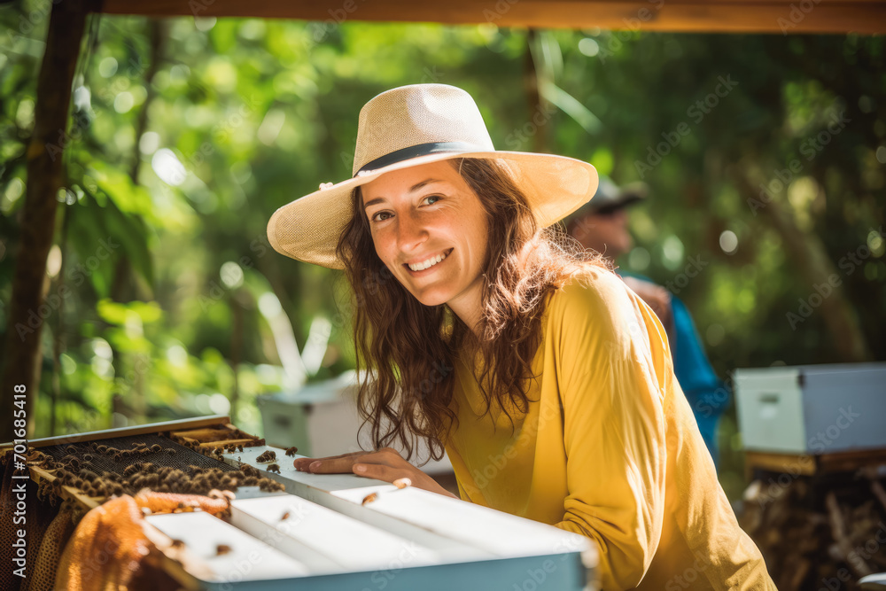 woman wearing full body protection against bees. Smiling. Behind is bee ...