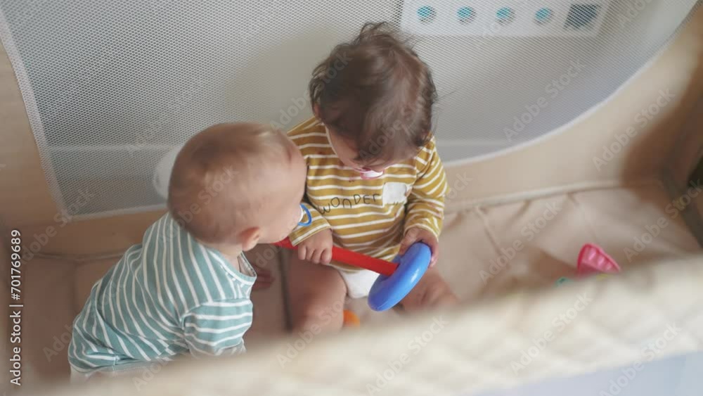 Vidéo Stock baby twins fight sitting in crib playpen. two baby toddlers ...