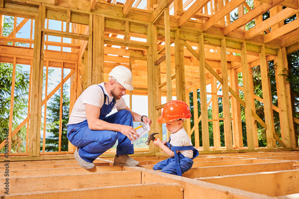 Father with toddler son building wooden frame house. Male builder ...