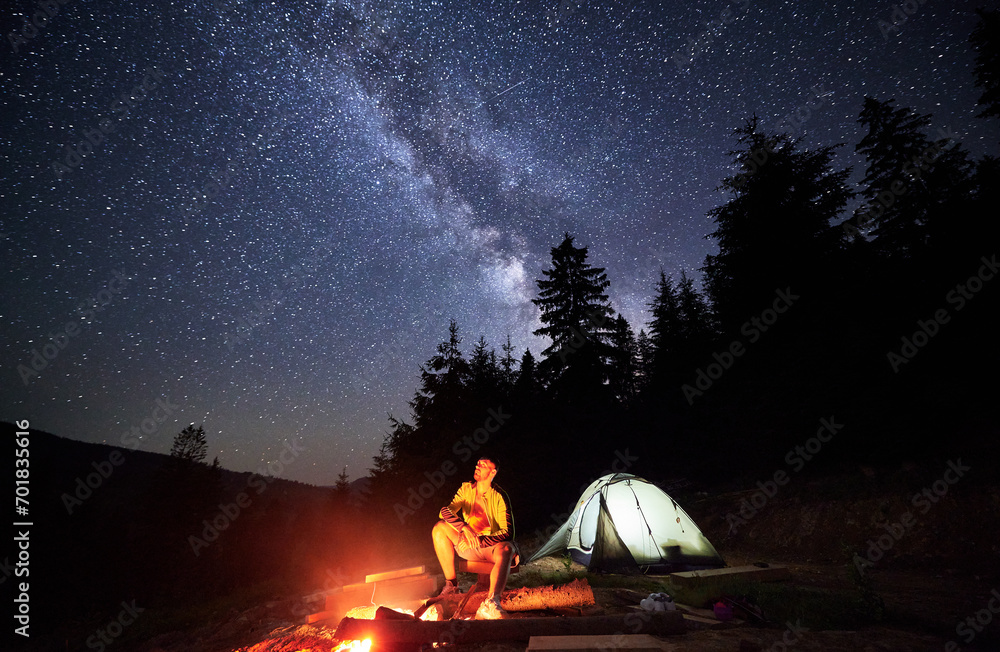Night-time camping expedition in mountains, beneath stars. Male ...