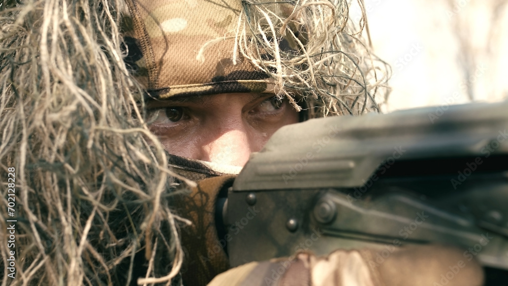A close-up of a sniper wearing a camouflage suit or grass cloak ...