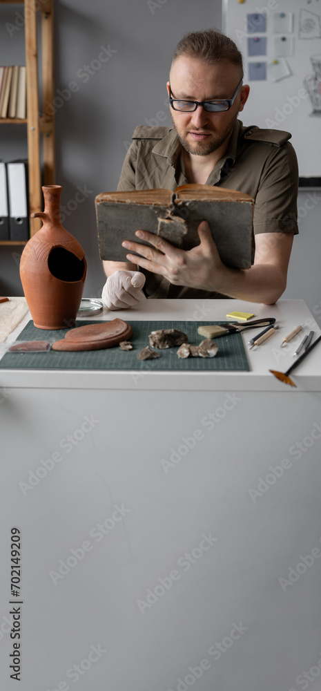 Archaeologist reading an old book working in his office studying ...