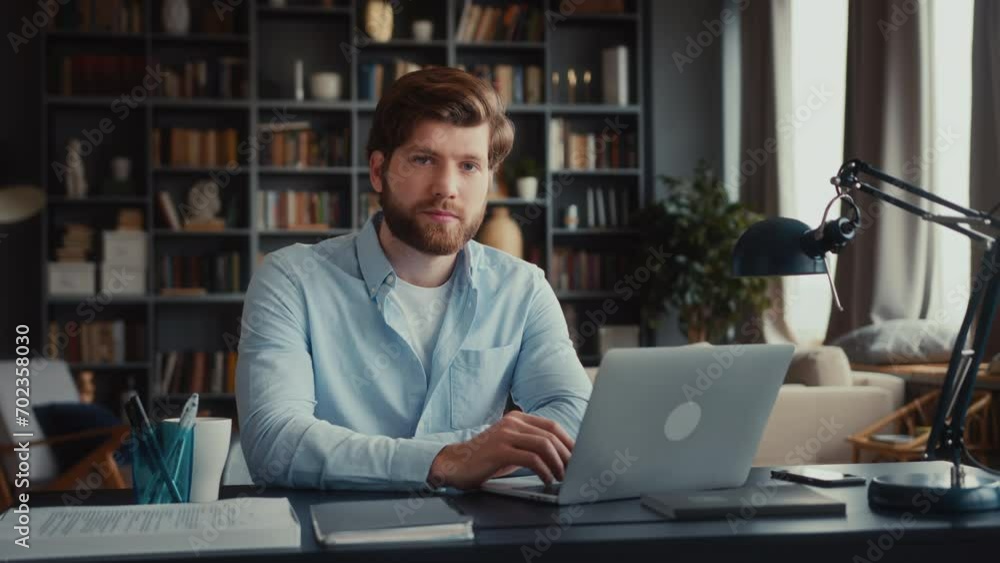Vidéo Stock portrait of young focused man with beard in blue shirt sits ...