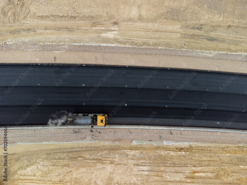 yellow truck pouring bitumen over a new road. Aerial drone shot. Road ...