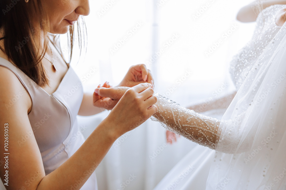 Morning of the bride. The bride's maid of honor helps the bride lace up ...