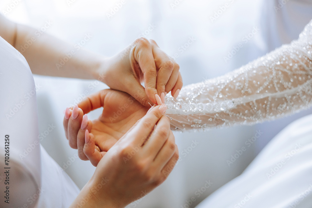 Morning of the bride. The bride's maid of honor helps the bride lace up ...