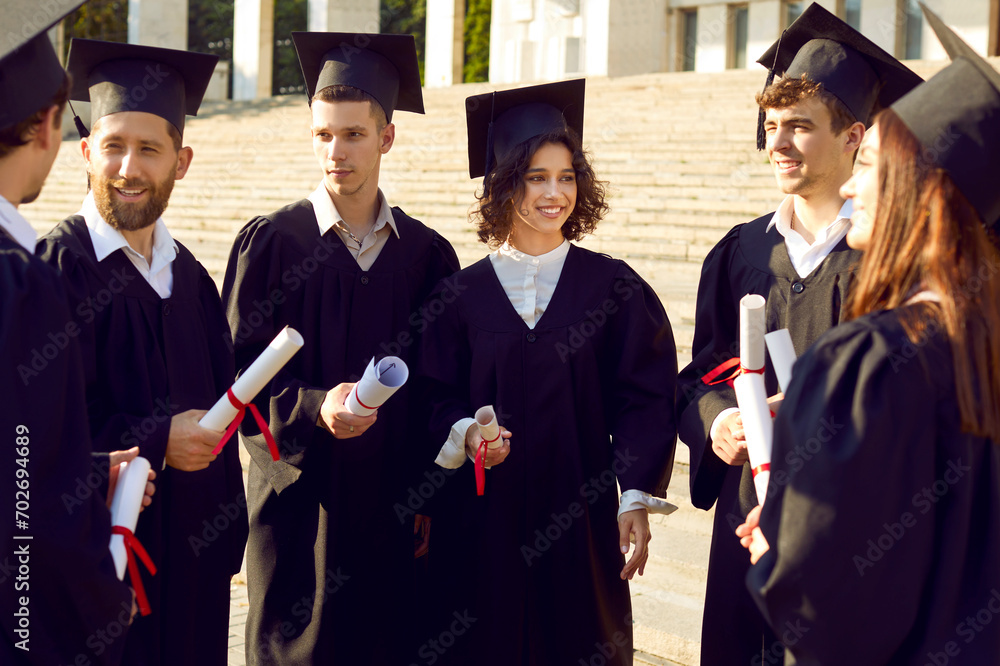Group of a happy smiling graduate students in black graduation robes ...