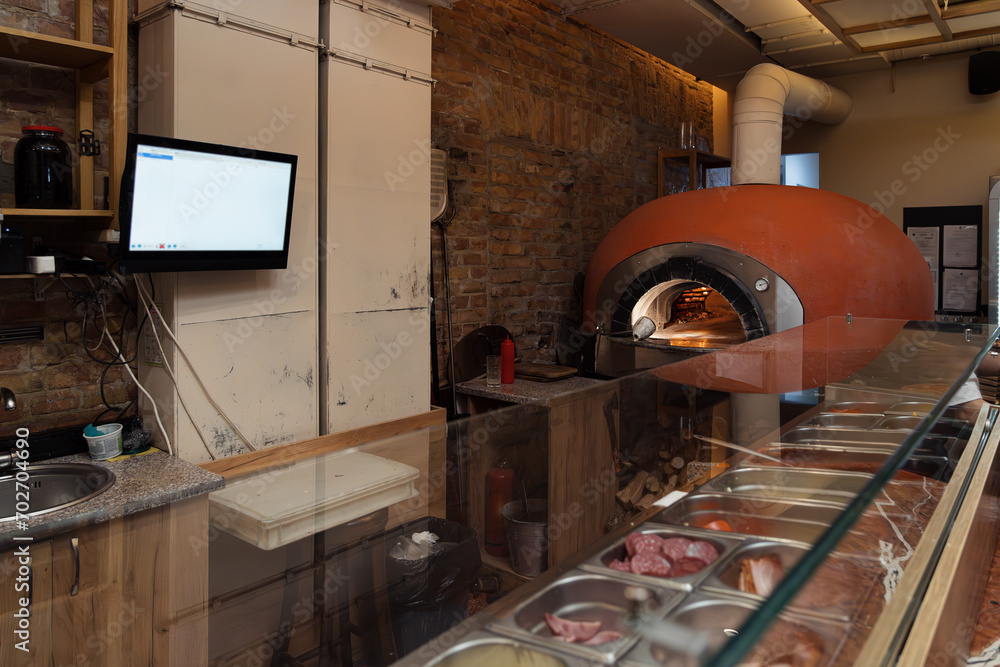 The interior of a pizzeria showcasing a wood-fired oven and a counter ...