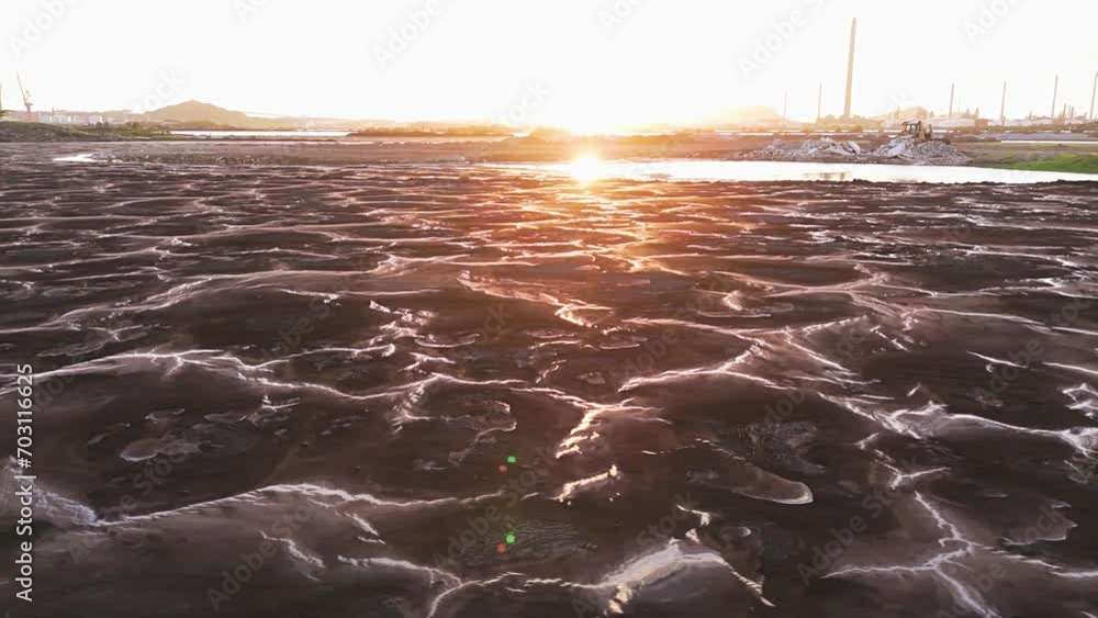 Sunlight glistens against polluted water in asphalt lake at golden hour ...