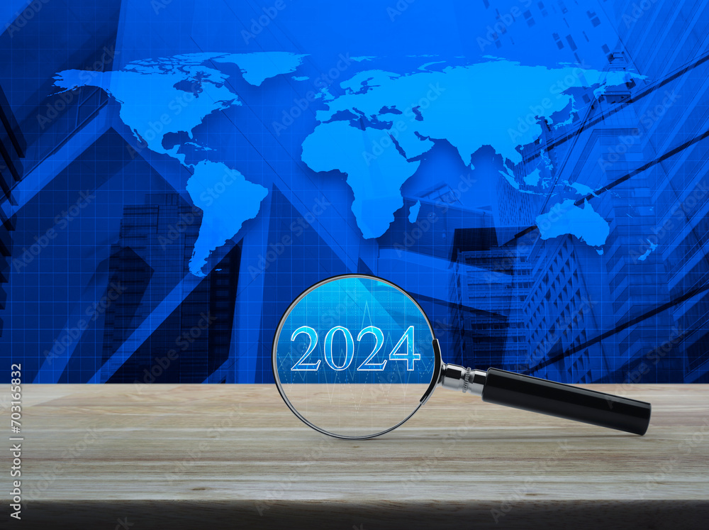 Magnifying glass with 2024 text and financial graph on wooden table ...