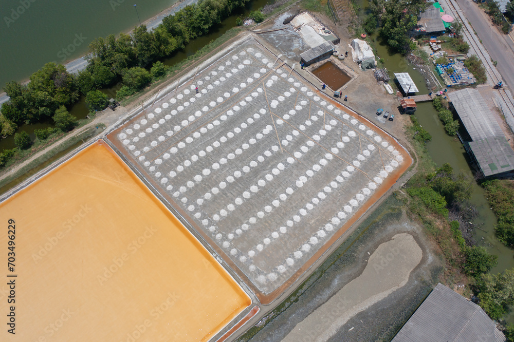 Aerial top view of farmers making heaps of raw sea salt piles with sea ...