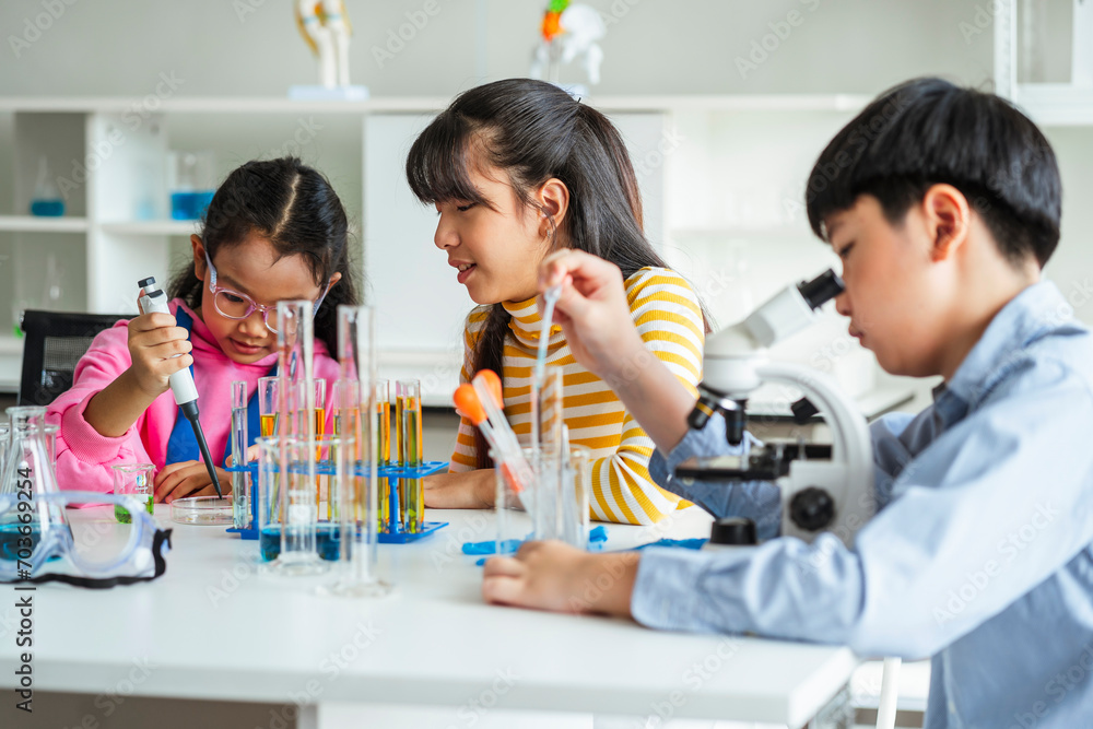 Group of school children using microscopes to study science at school ...