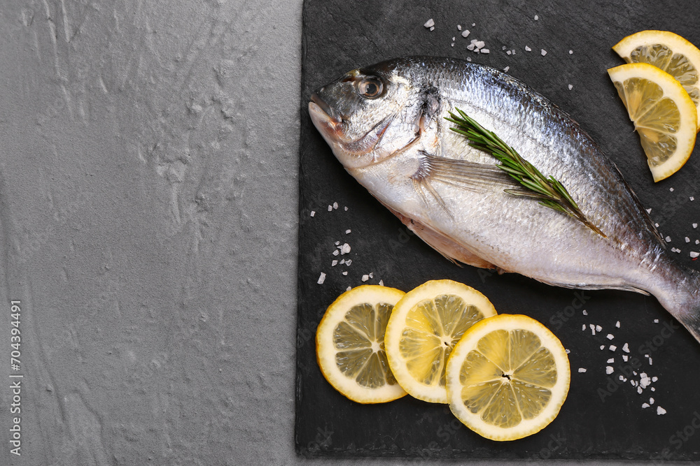 Slate board of raw dorado fish with lemon on grey background Stock ...