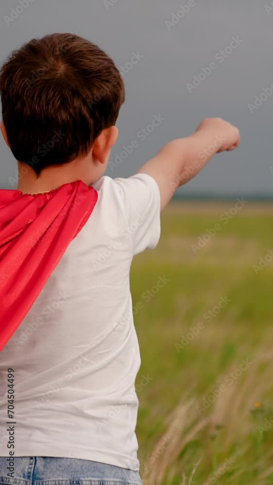 Little hero in red cloak looks into distance. Boy kid plays superhero ...
