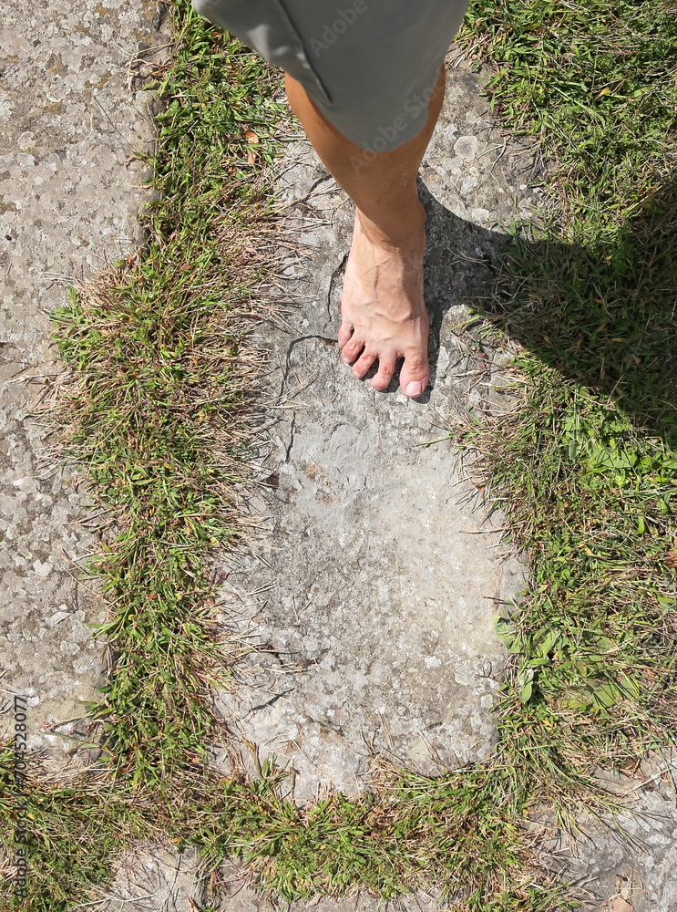 barefoot man walking on the stones of the very ancient Roman road going ...