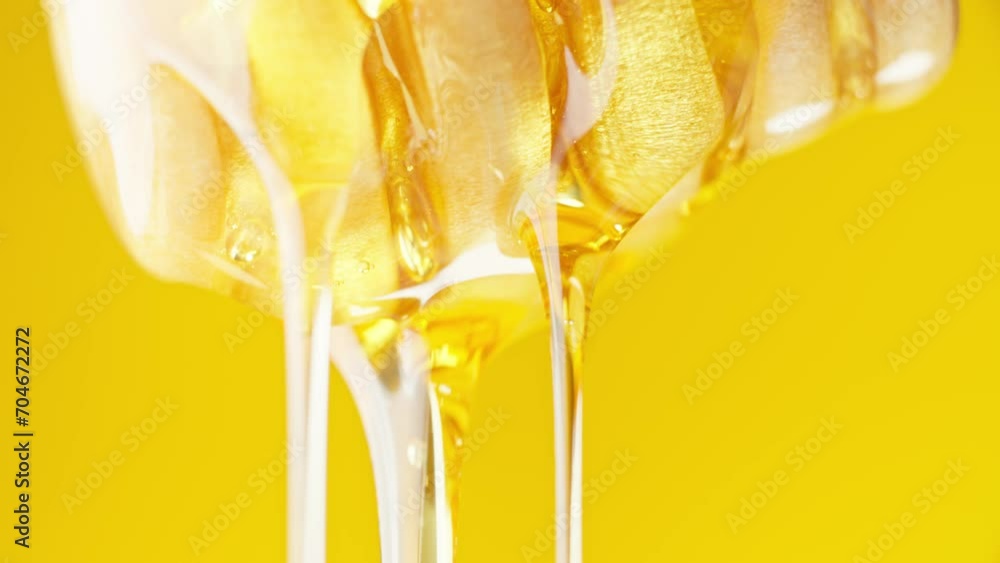 Honey dripping from wooden honey spoon at yellow background. Fresh ...