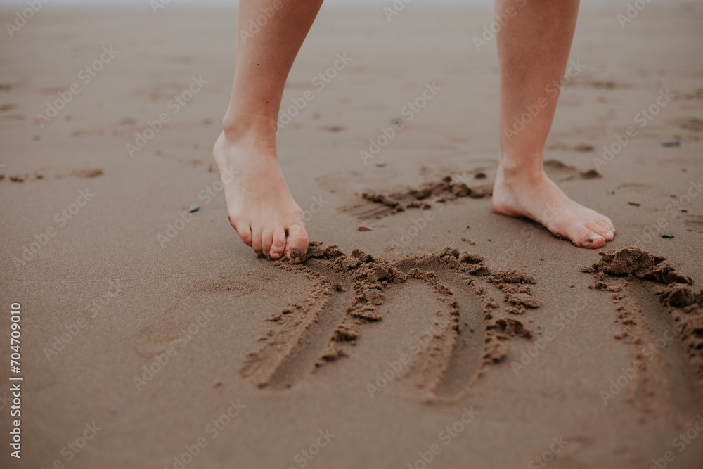 Drawing on the sand with your feet. Women's legs. Exercise against flat ...