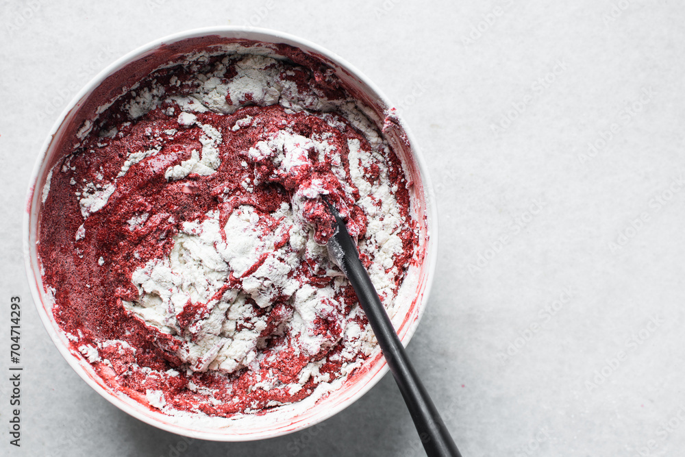 Top view of flour being folded into Red velvet cake batter in white ...