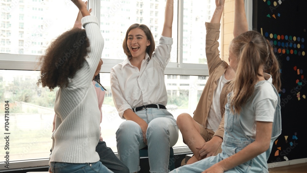 Caucasian teacher and diverse students raised hands at classroom. Young ...