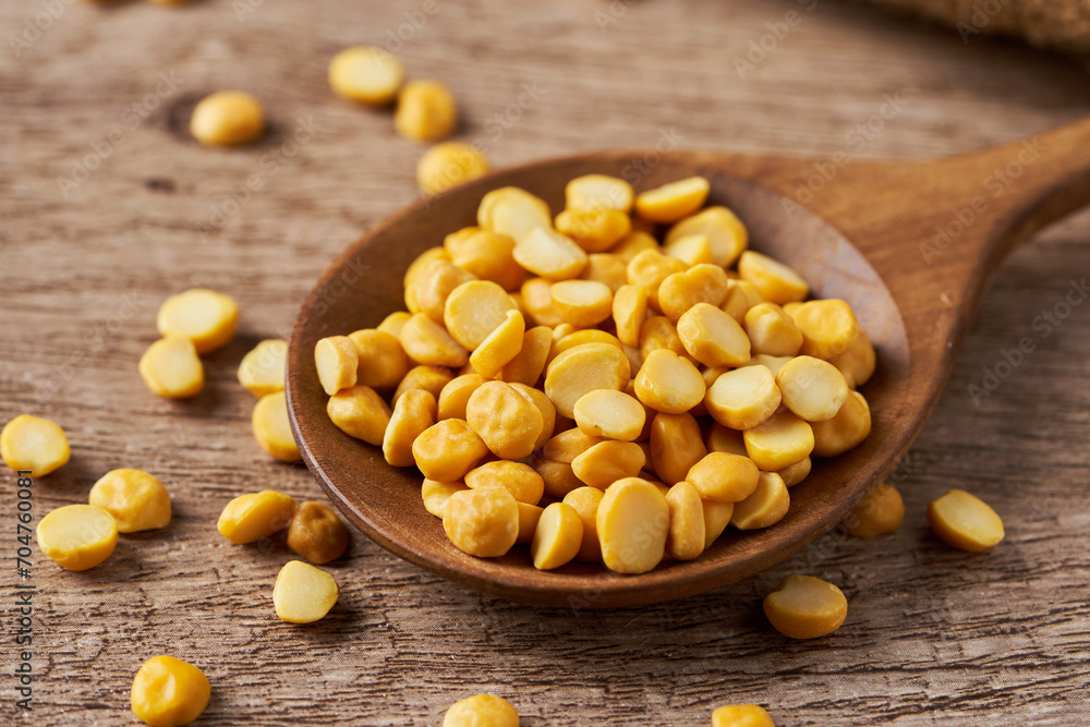 pile of split bengal gram or chana dal in wood spoon on wood table ...