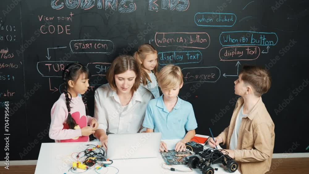 Diverse student writing engineering code while boy fixing mother board. Teacher giving advice ...