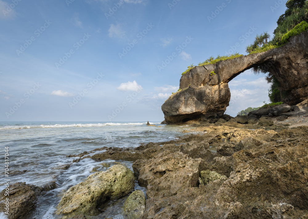 Natural bridge arch at the rocky scenic coast of a tropical Shaheed ...